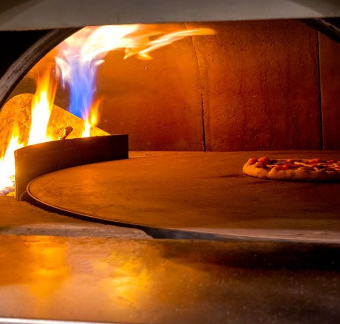 Rotating pizza oven internal hearth with wood fire
